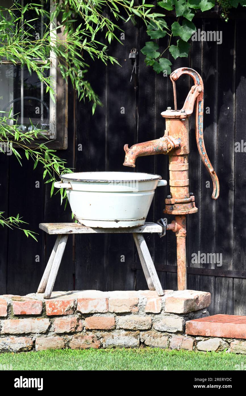 Old vintage water pump with white metal basin in rustic countryside ...