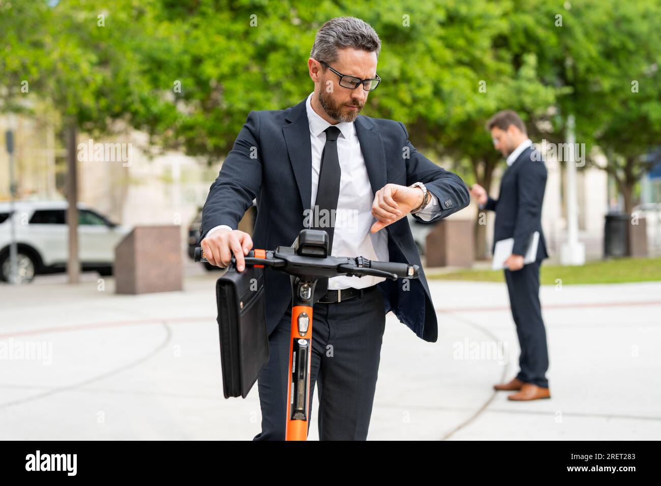 Attractive business man riding a kick scooter at New York park ...