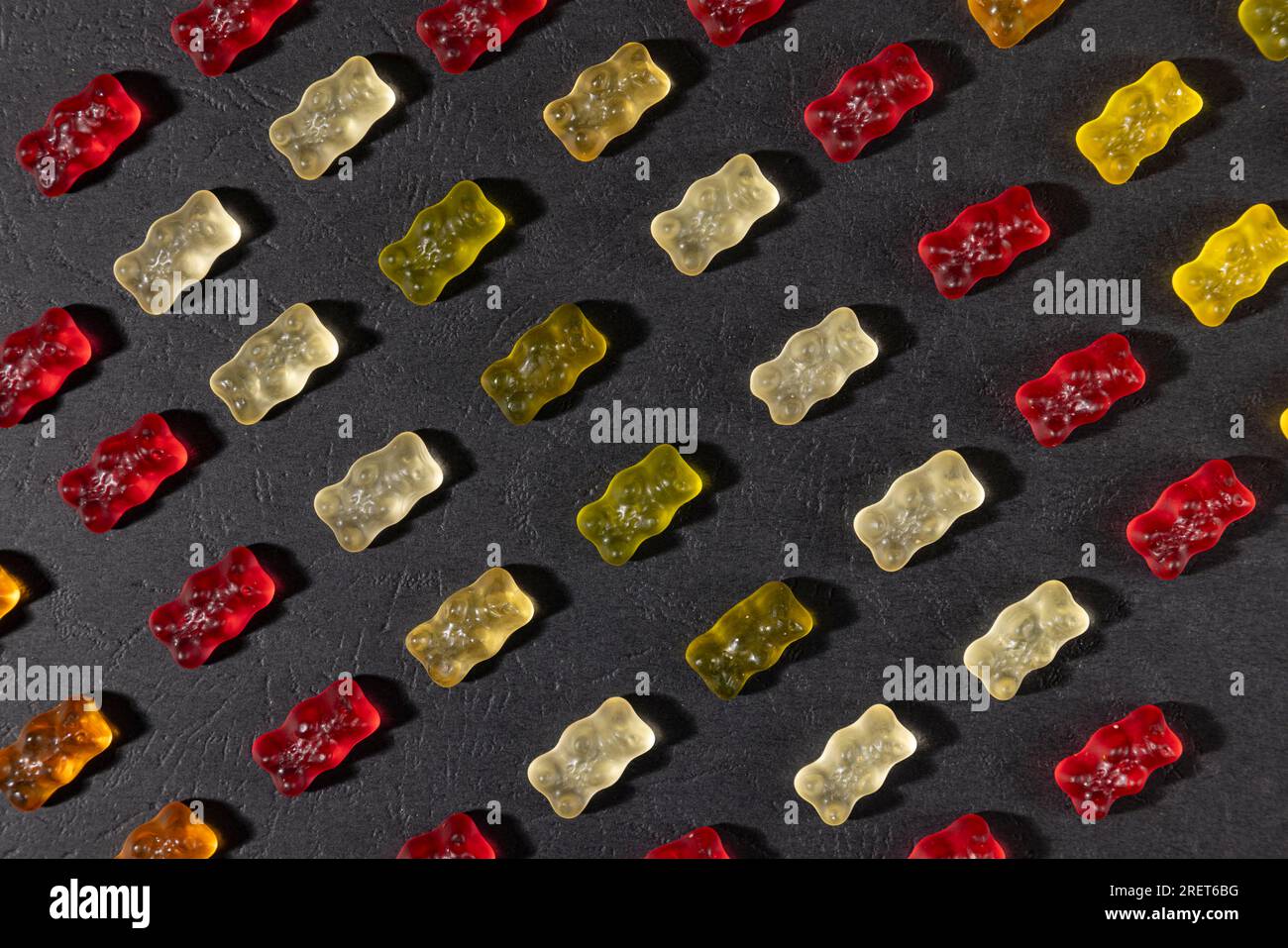 Different coloured gummy bears in rows, on a dark background Stock ...