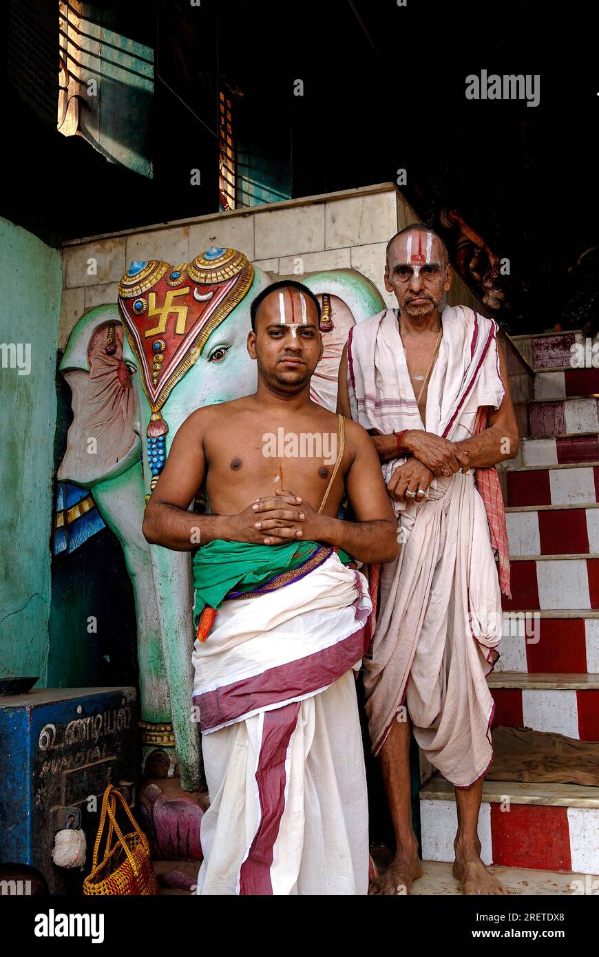 Two Vaishnavite men standing on the steps near the stucco elephant in ...