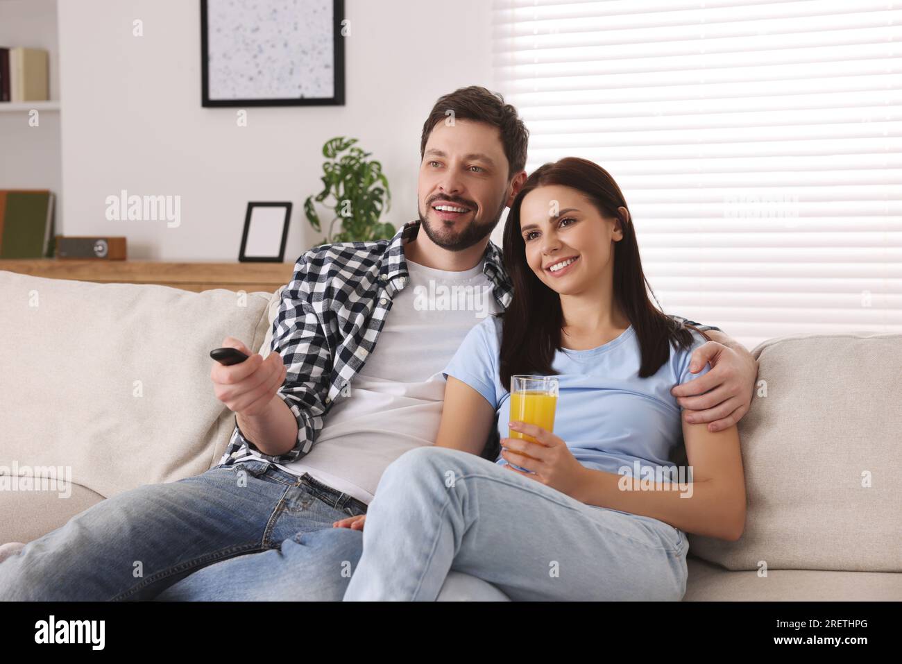 Happy couple watching show at home. Man changing TV channels with ...