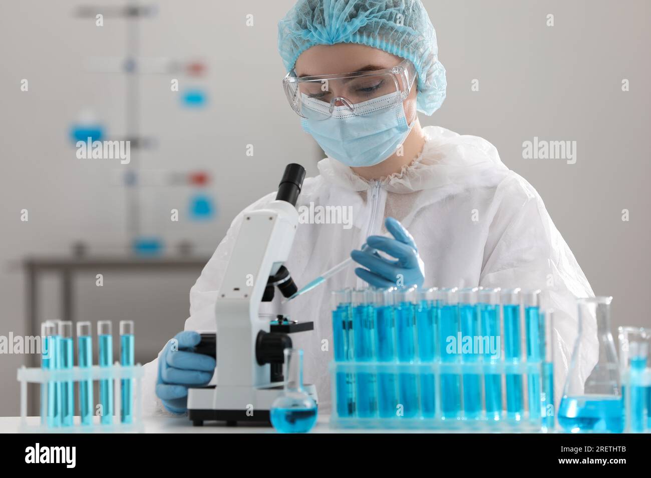 Scientist dripping sample onto Petri dish while working with microscope ...