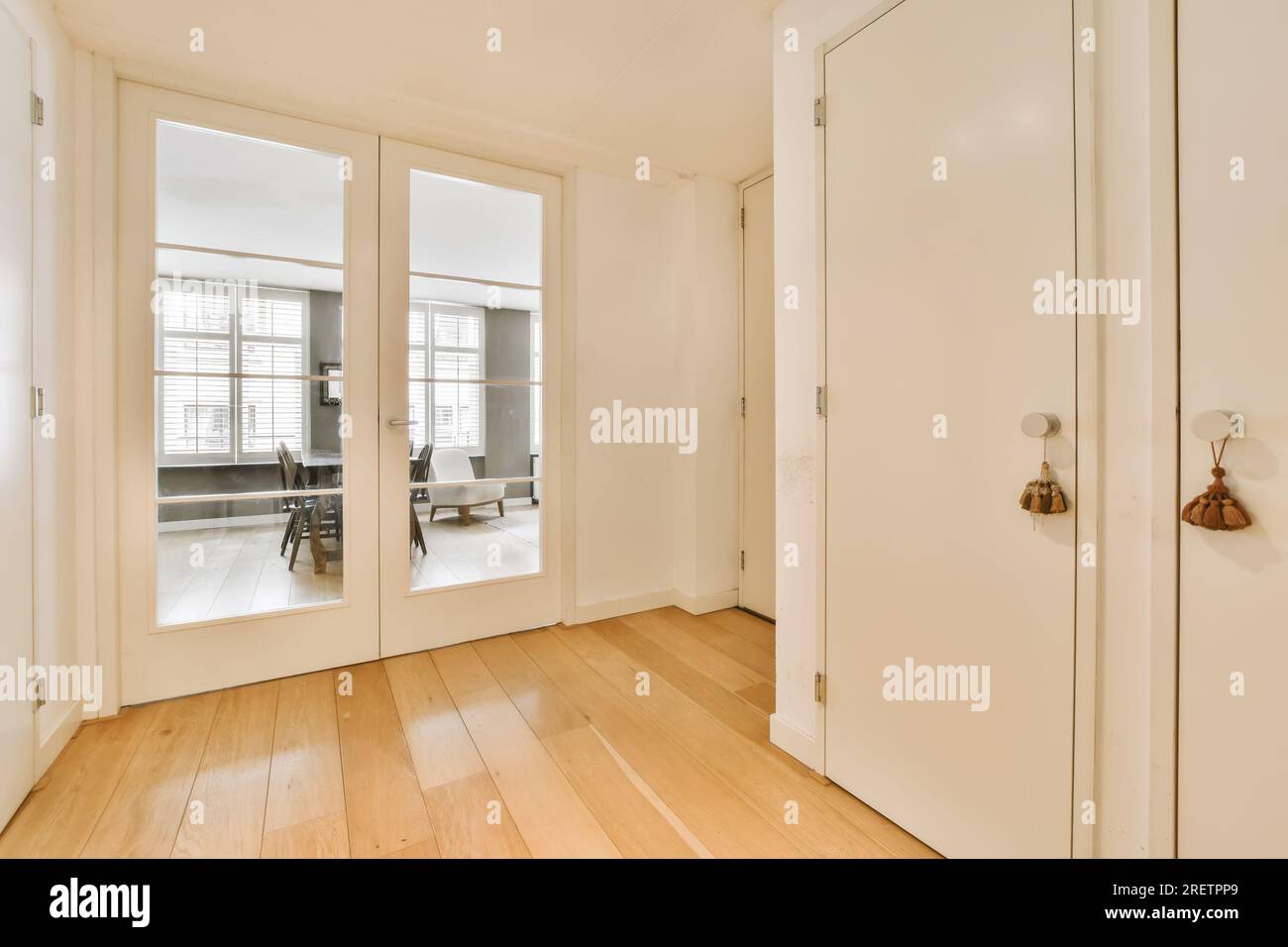 an empty room with wood flooring and white doors leading to the living ...