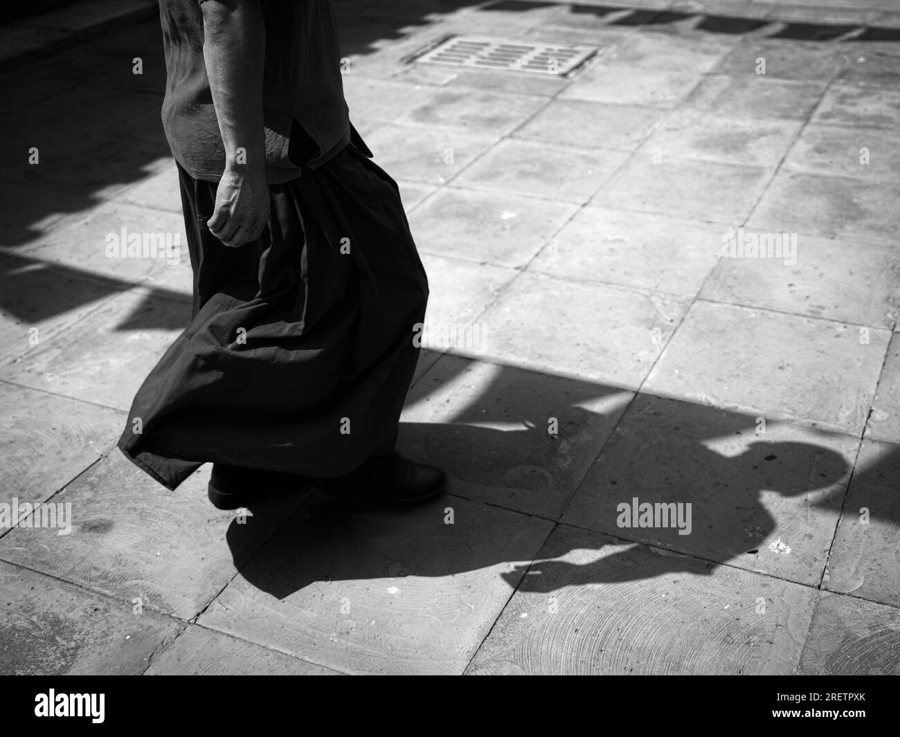 Buddhist Monk walking in early afternoon sunlight with a casted shadow ...