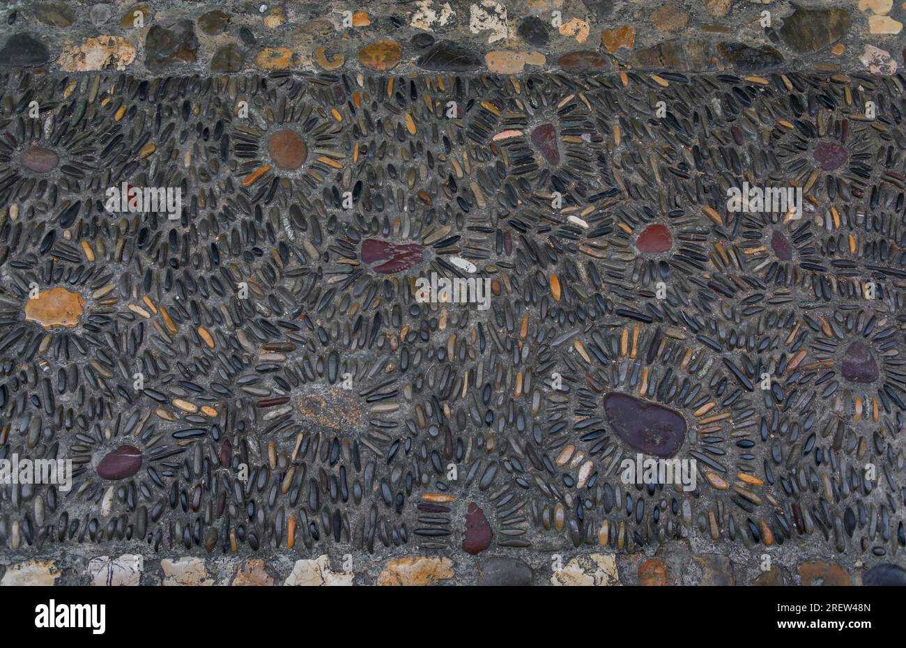 Ornate pebble mosaic street pavement between traditional houses on a ...