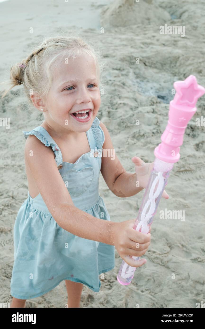 Cheerful cute toddler with container of soap bubbles laughing and ...
