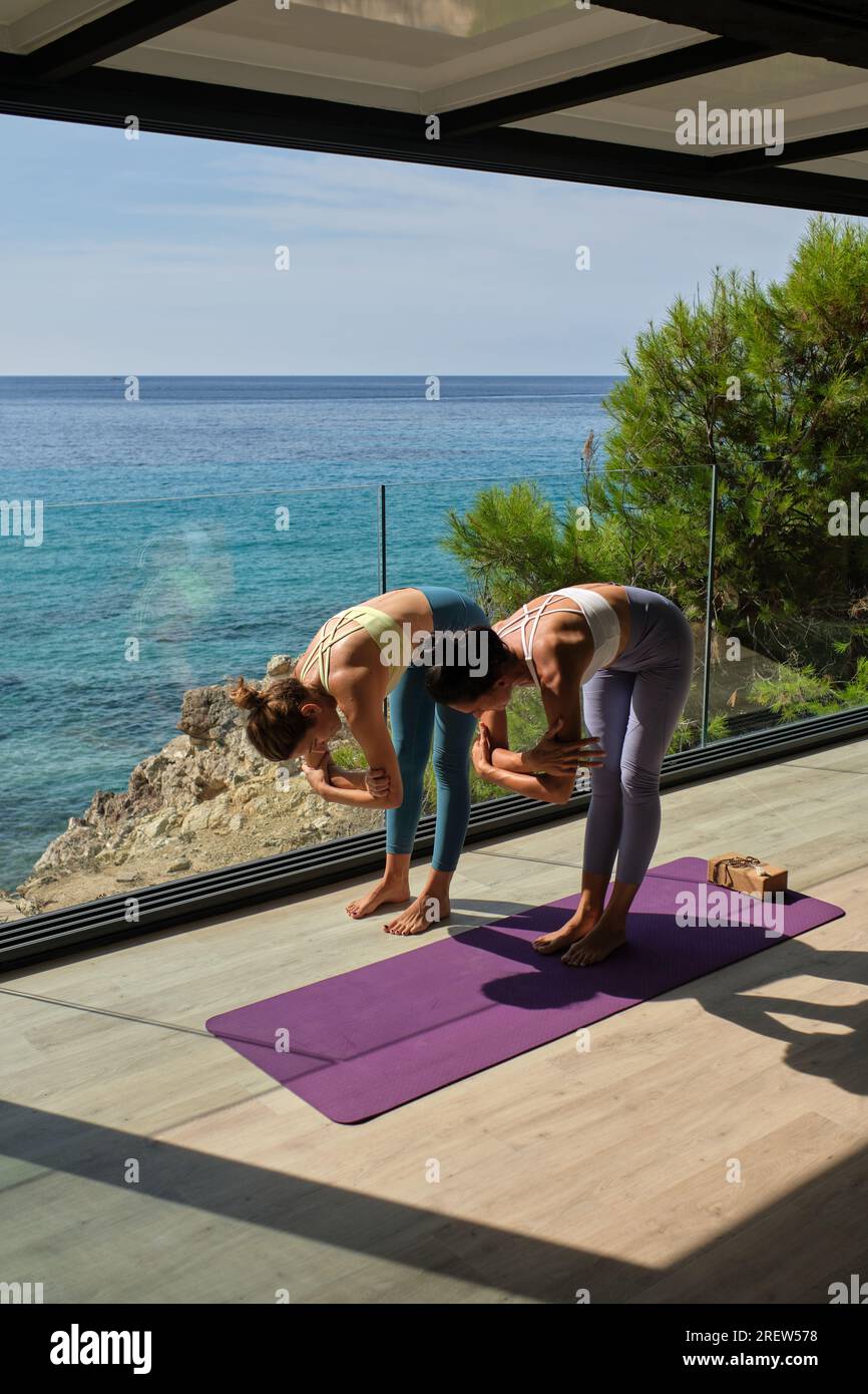 Full body of barefoot slim females doing forward bend exercise during ...