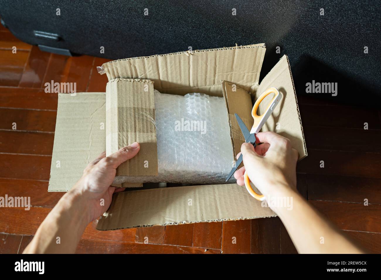 Opening cardboard parcel box with scissors Stock Photo - Alamy