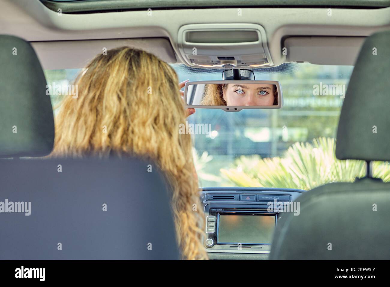 Back view young female driver with blue eyes and wavy hair looking at ...