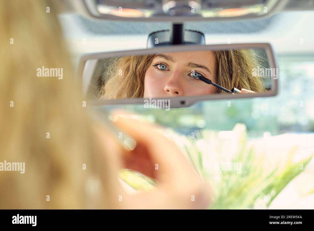 Crop beautiful female with blue eyes applying mascara and reflecting in ...