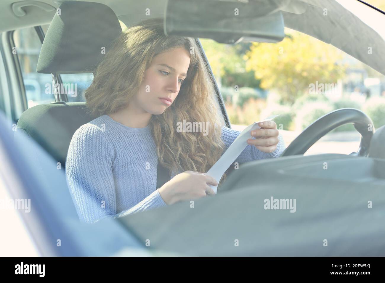 Worried young female driver in casual wear sitting in car drivers seat ...