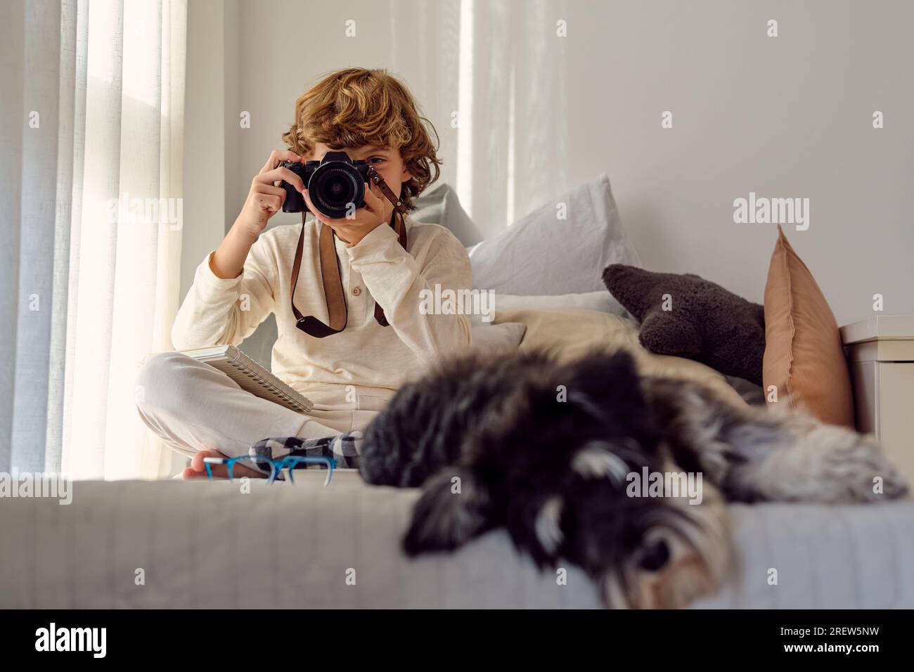 Anonymous kid with crossed legs taking photo on professional camera ...
