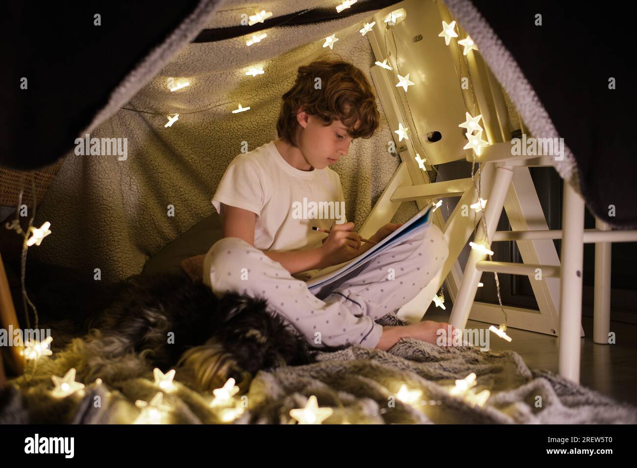 Full body of talented boy drawing in sketchbook while sitting with ...