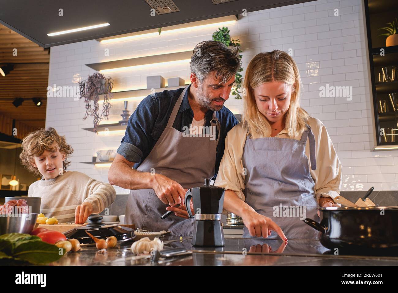 Parent turning on modern stove with pot at table with various ...
