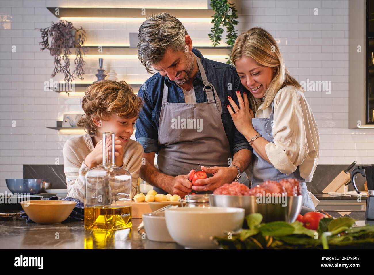 Content wife hugging man preparing tomatoes at table with various ...