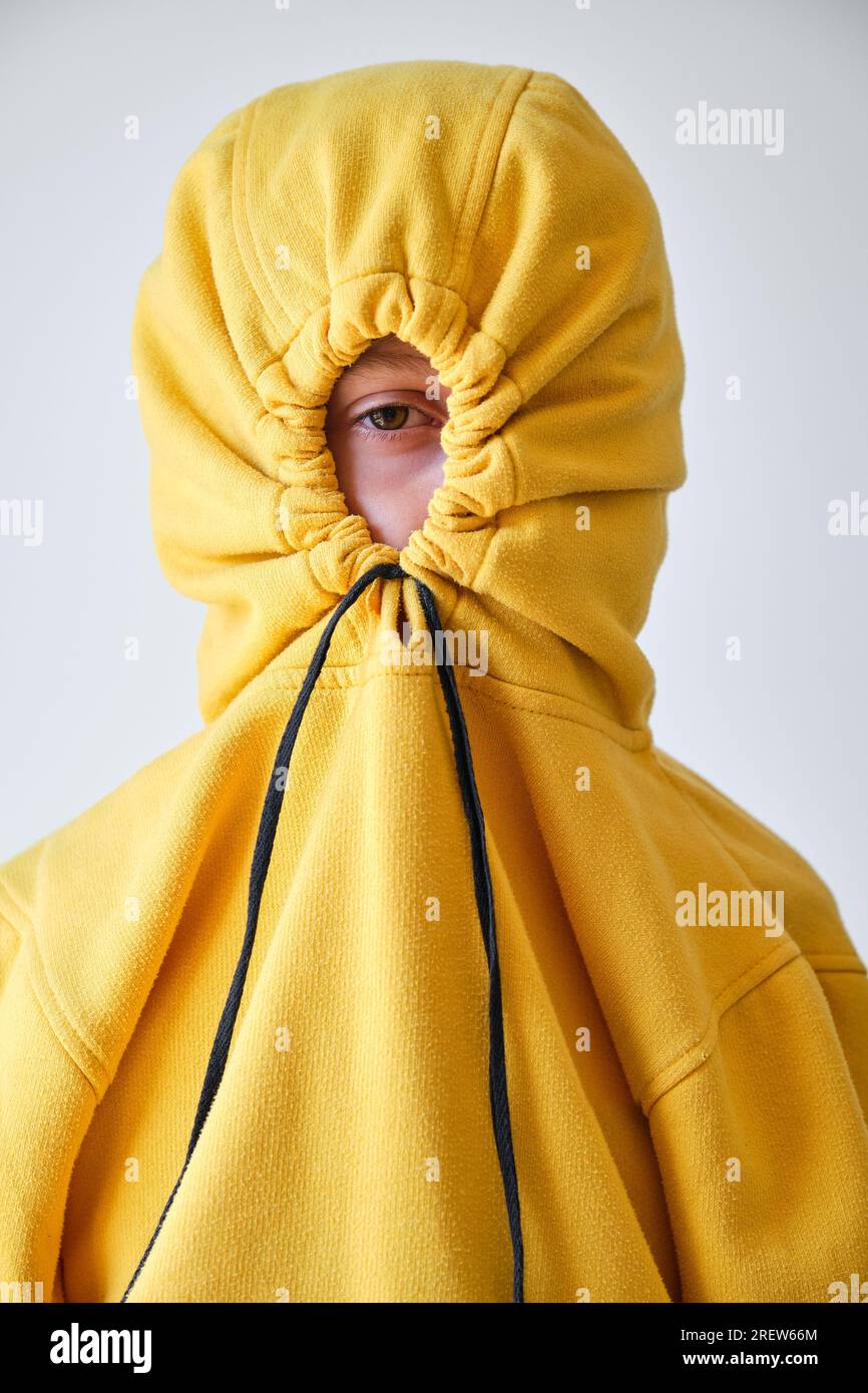 Anonymous child having yellow hood tightened around eye while looking ...