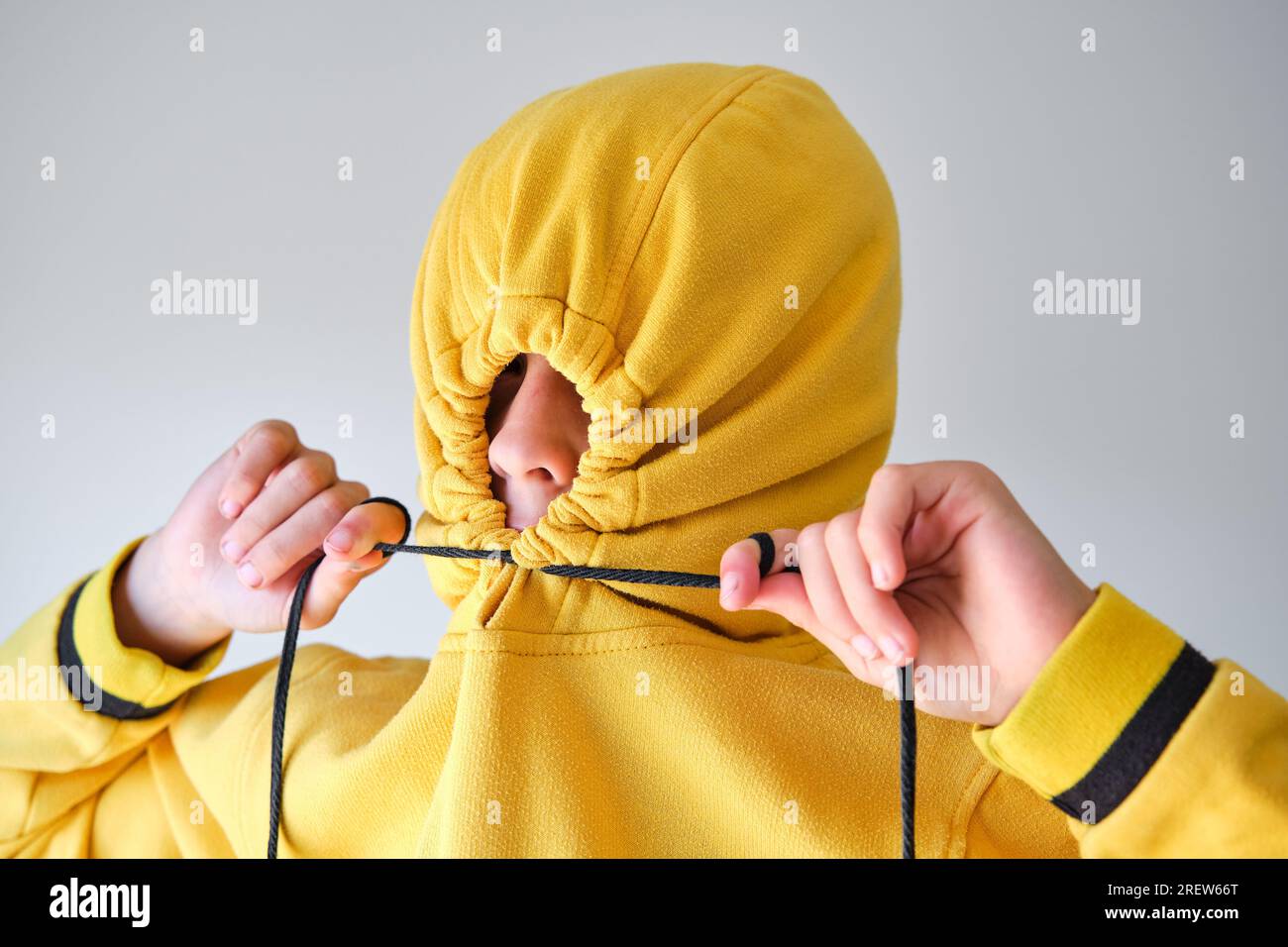 Unrecognizable child in yellow hoodie tightening laces on hood over ...