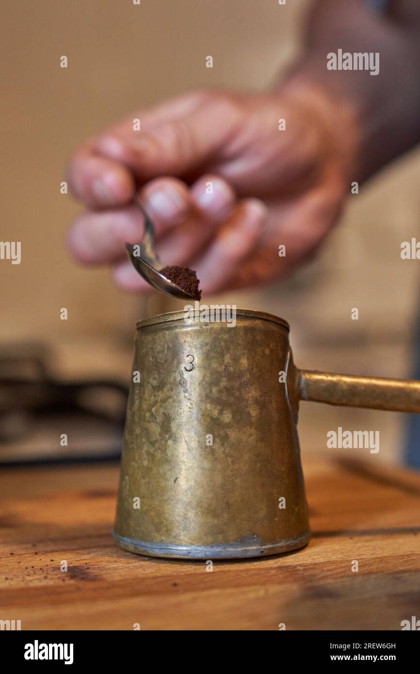 Crop anonymous man pouring aromatic coffee in metal cezve placed on ...