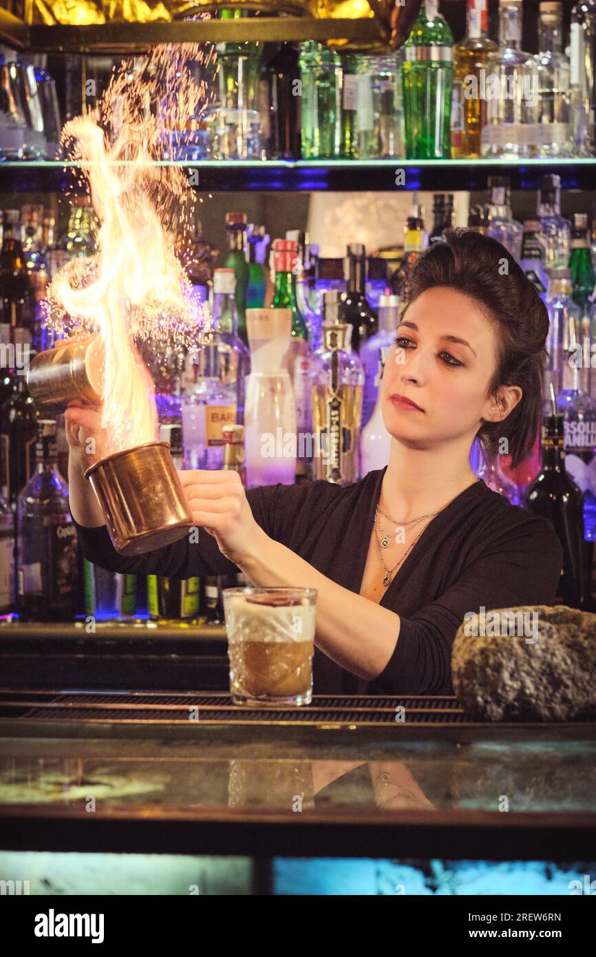 Concentrated skilled young female bartender with dark hair adding salt ...