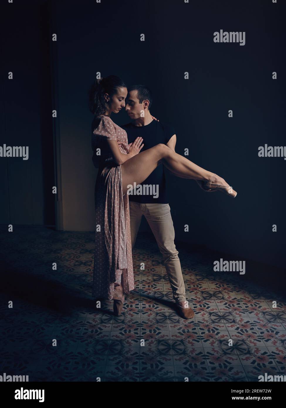 Full body side view of ballerina in pointe shoes standing with raised ...