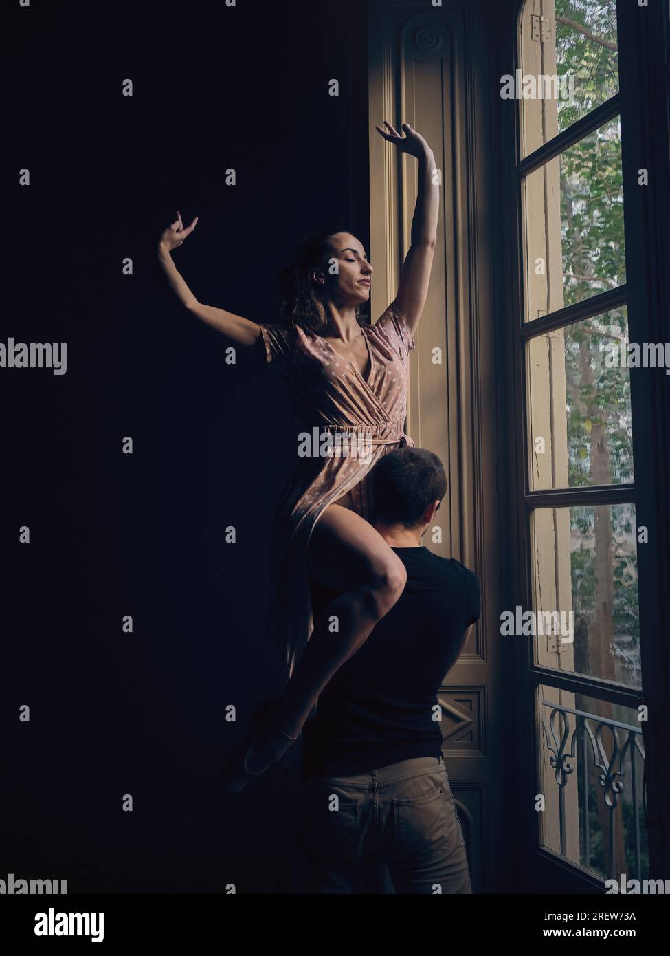 Talented ballerina in dress sitting on shoulder of faceless male dancer ...