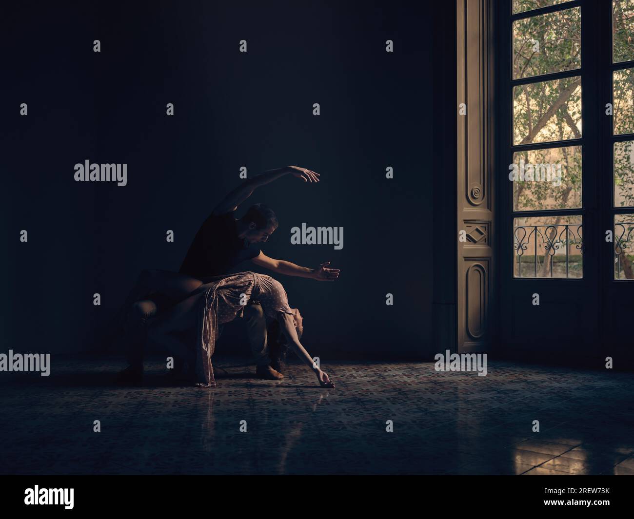Full body of flexible ballerina lying on knees of male dancer while ...