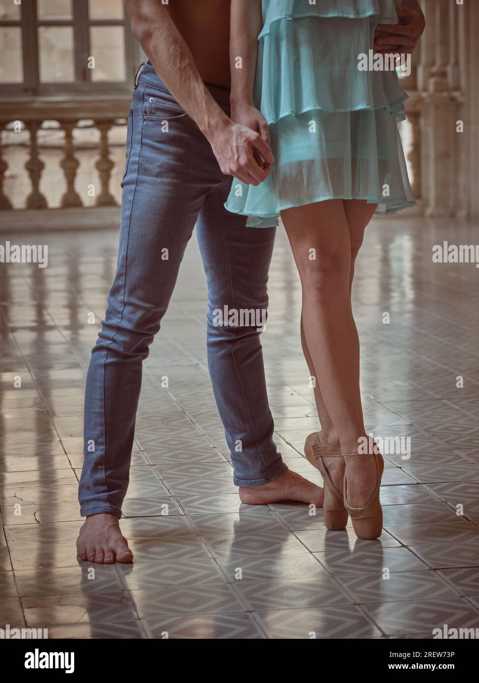 Crop unrecognizable ballerina and male ballet dancer in denim holding ...