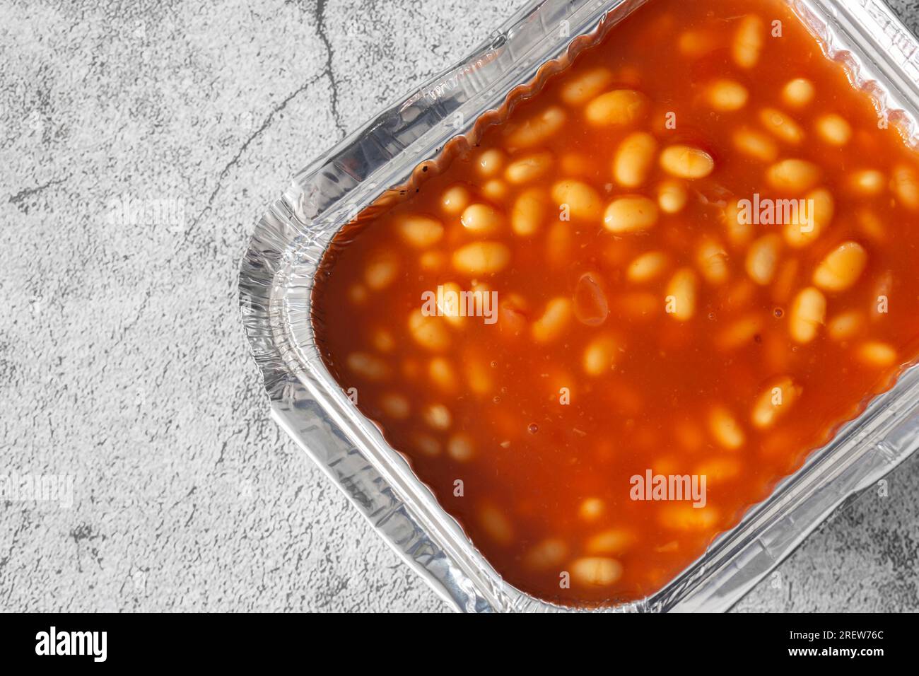 Baked beans, in a tomato sauce, in a takeaway foil tray carton ...