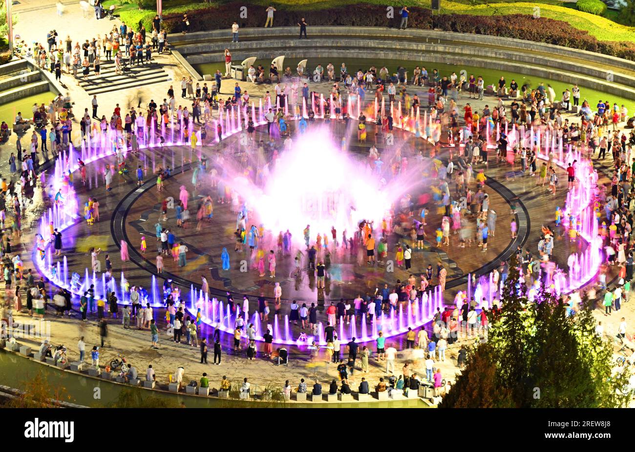 KORLA, CHINA - JULY 28, 2023 - People cool off in front of a music ...