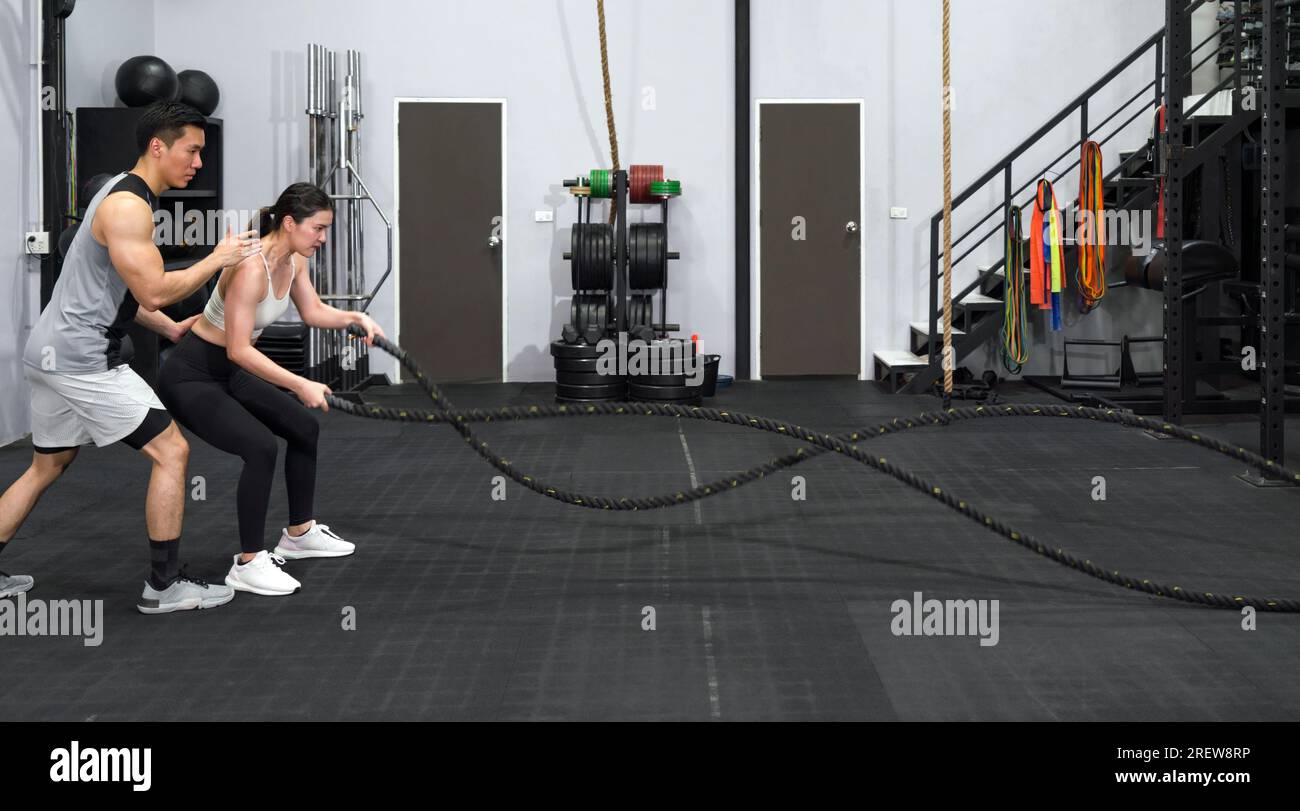 Fitness-focused couple immersed in an intense rope workout at a well ...