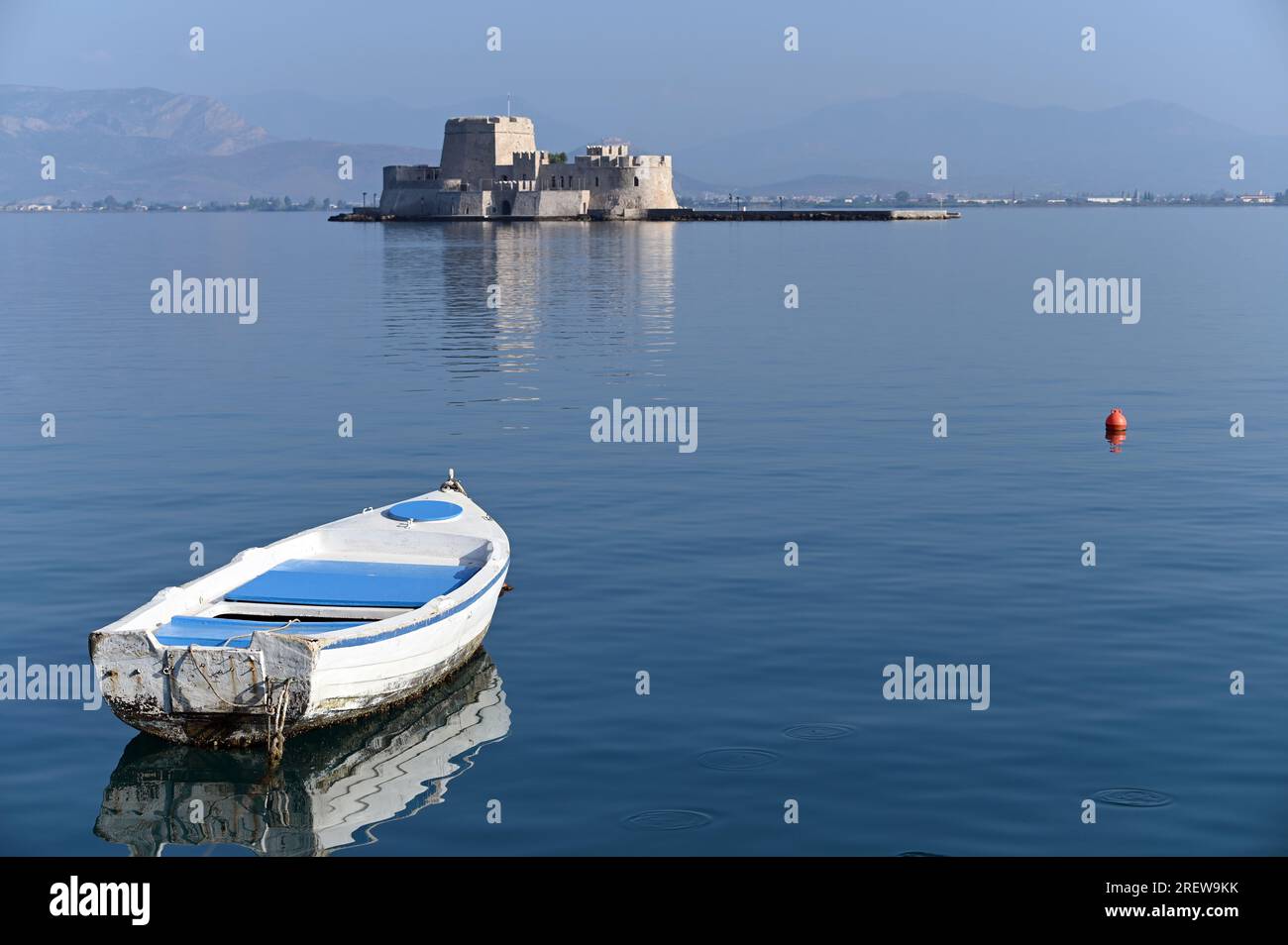 Small white boat and an Bourtzi fortress in Nafplio, Peloponnese ...
