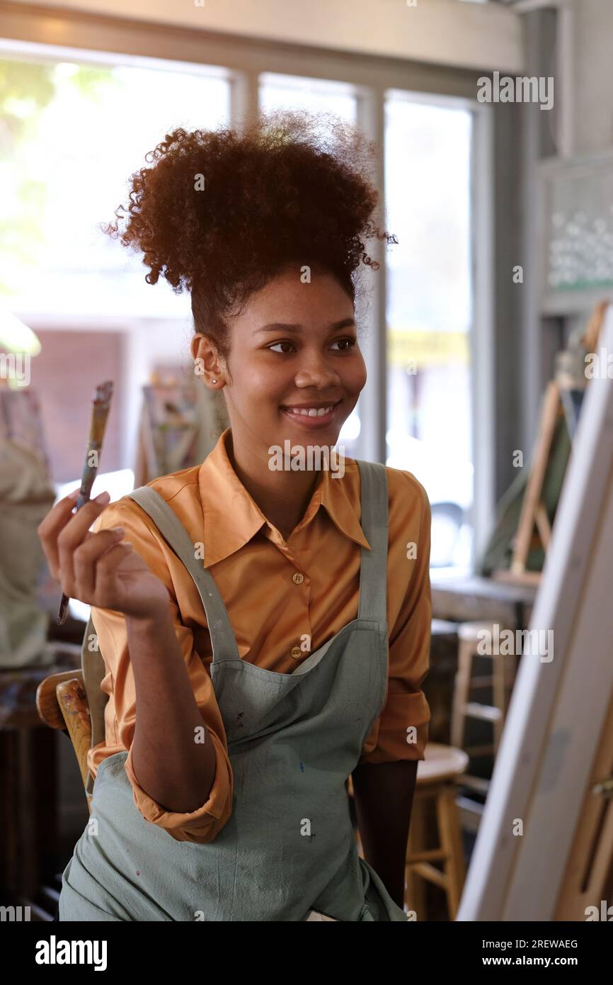 Smiling African American female artist creating masterpiece, painting ...