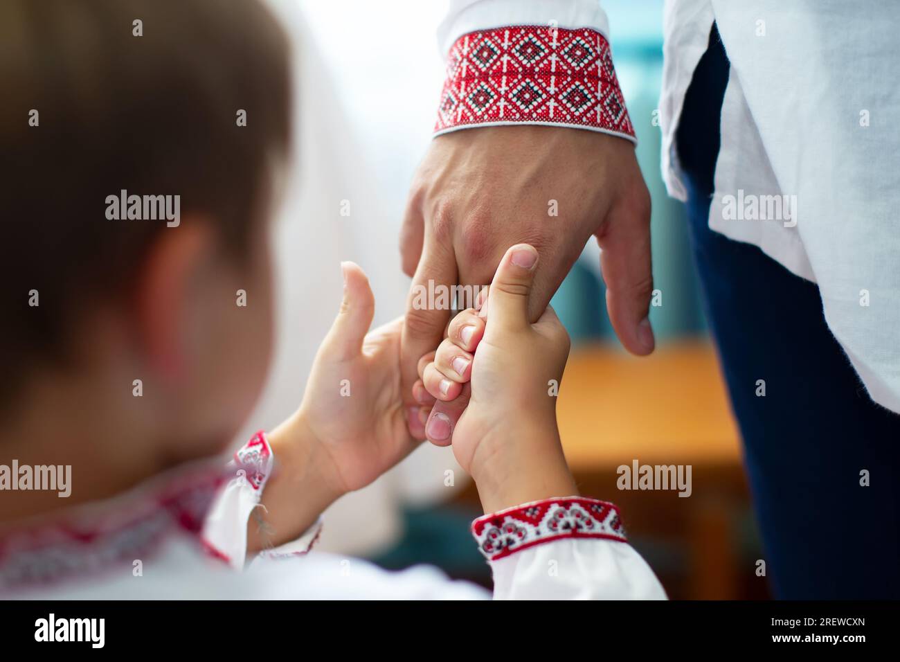 The hand of an adult holds the hand of a child, they are dressed in ...