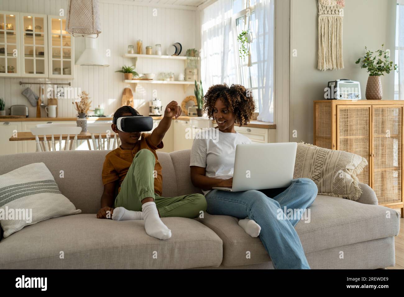 Modern african american family, mom and son sit on sofa with electronic ...