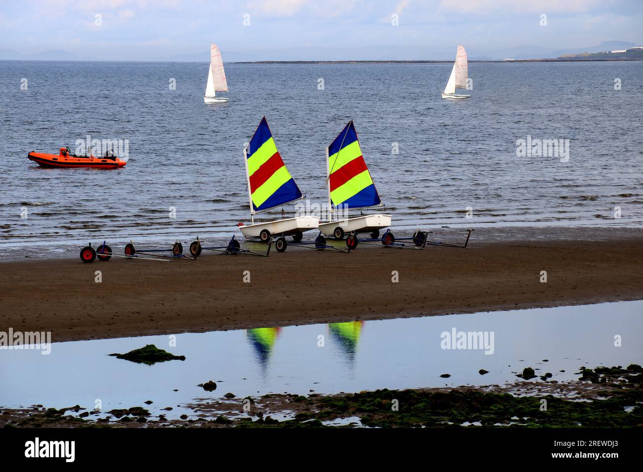Small sailing dinghy boats with colourful sails at a coastal beach ...