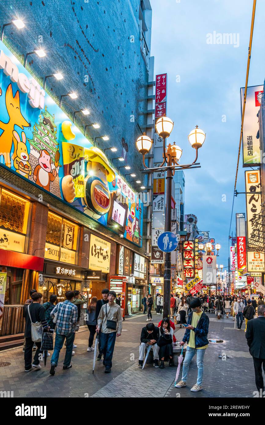 View along Dotonbori at early evening, busy with people. Foreground ...