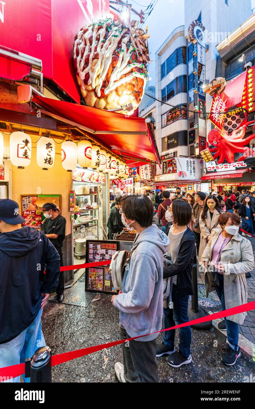 People queuing to buy takoyaki, octopus balls, at the takeaway counter ...