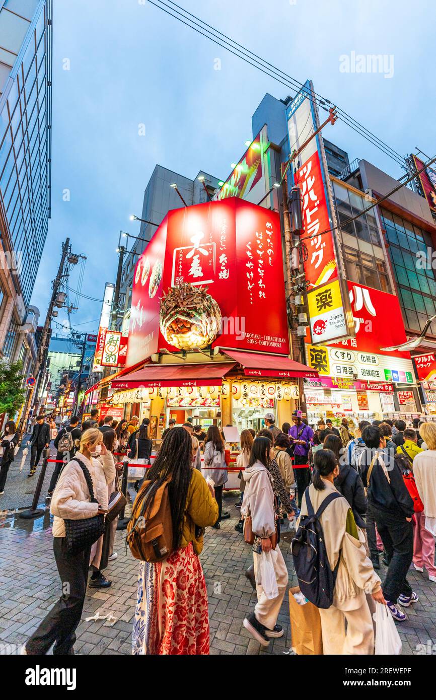 Busy scene with people both queuing and walking by the popular Takoyaji ...
