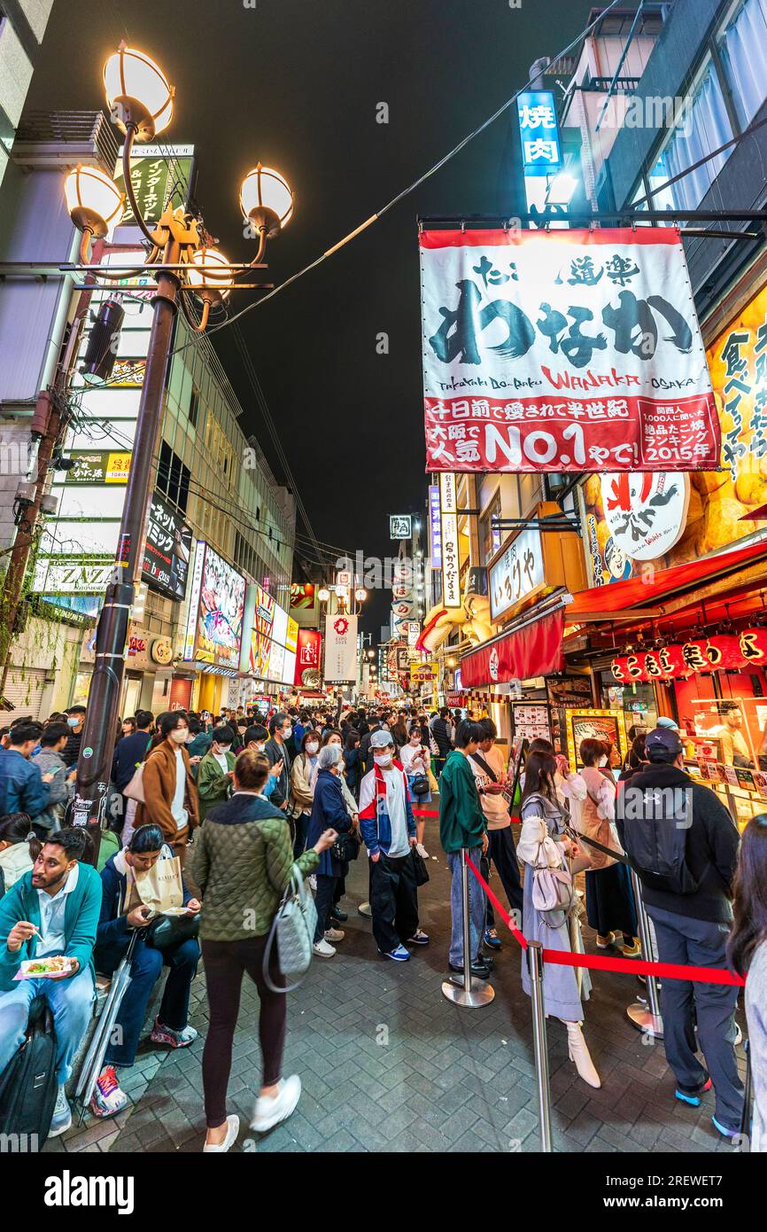 View along a busy and lively night time Dotonbori street, Osaka, with ...