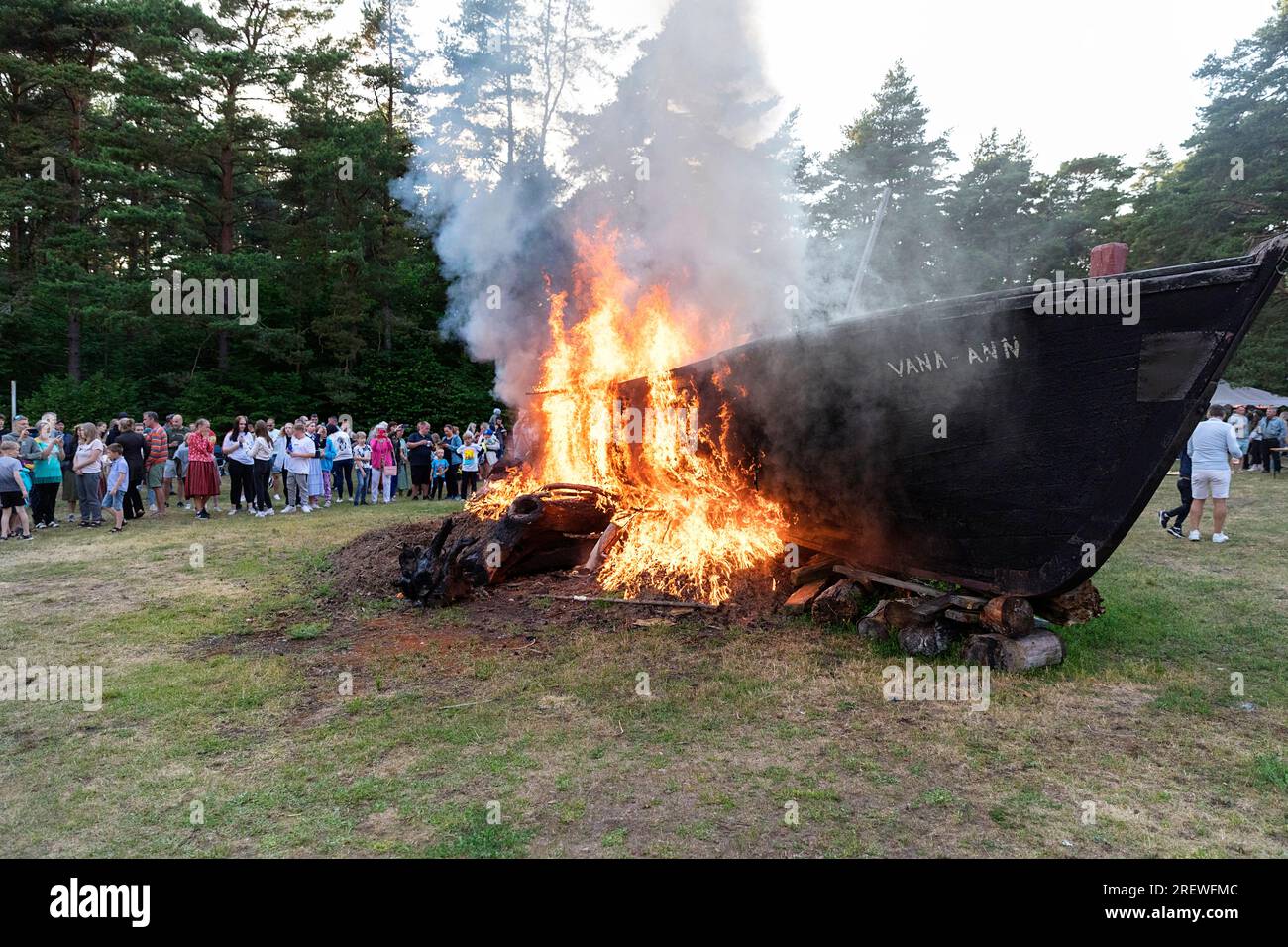Local people standing around bonfire (burning sailing boat) on ...