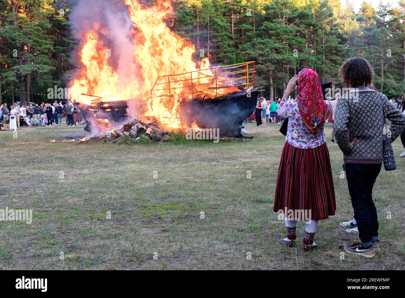 A couple in traditional estonian folk costumes near burning ship ...