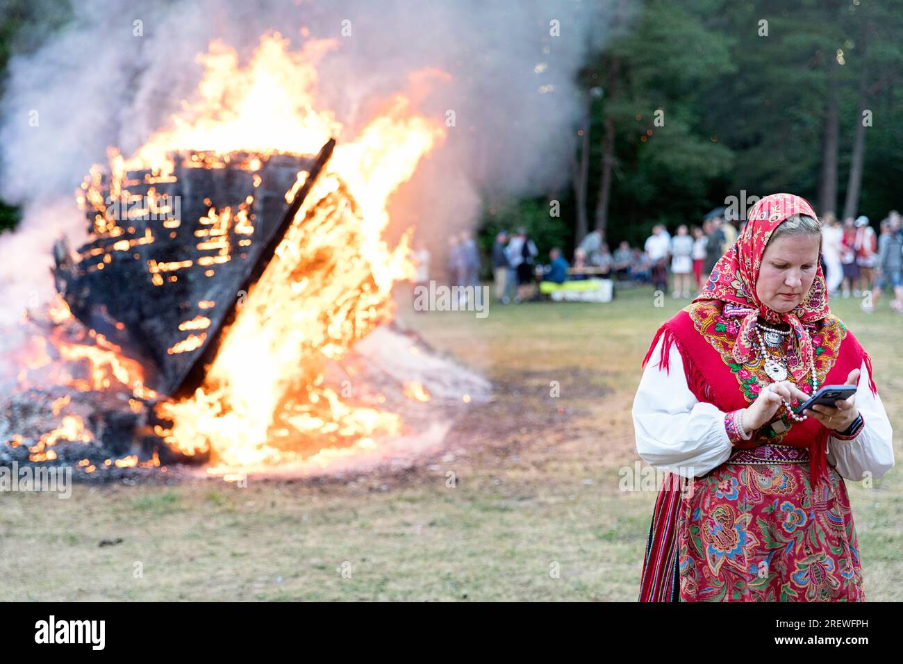 Local woman in traditional kihnu folk dress looking at the mobile phone ...