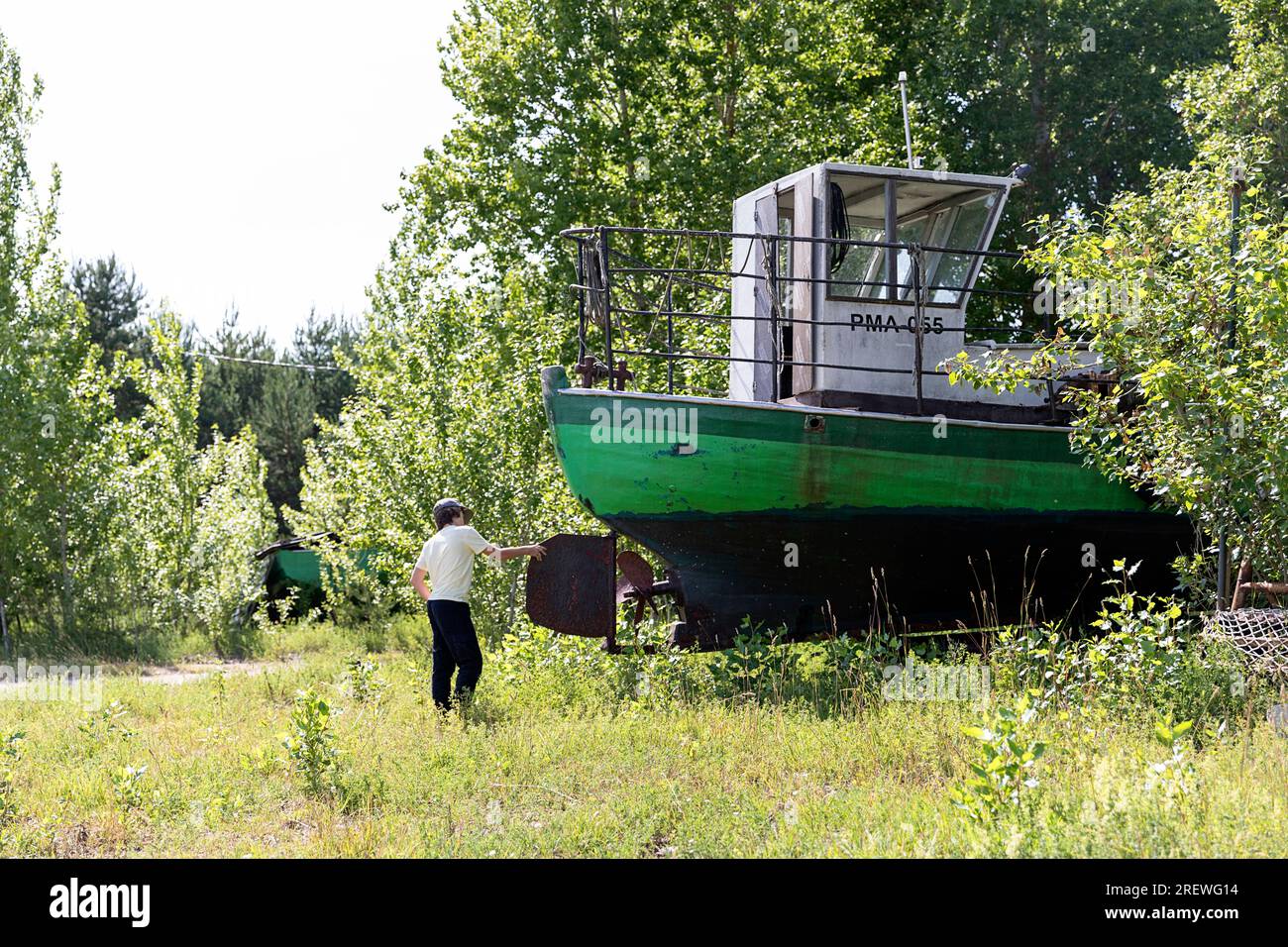 Boy tourist exploring Old abandoned wooden fishing boat in a forest on ...