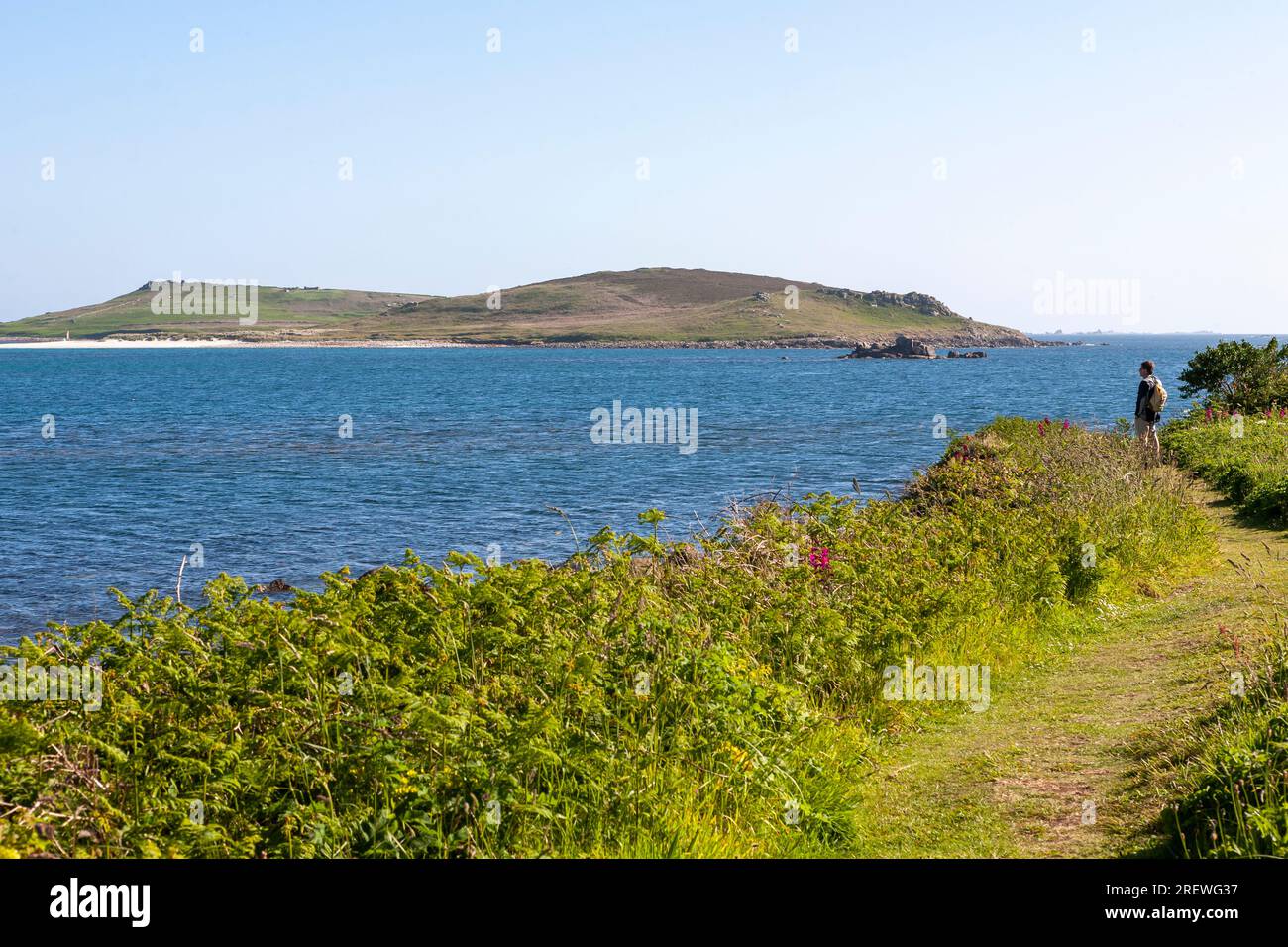 A walker looks at the uninhabited island of Samson from across the ...