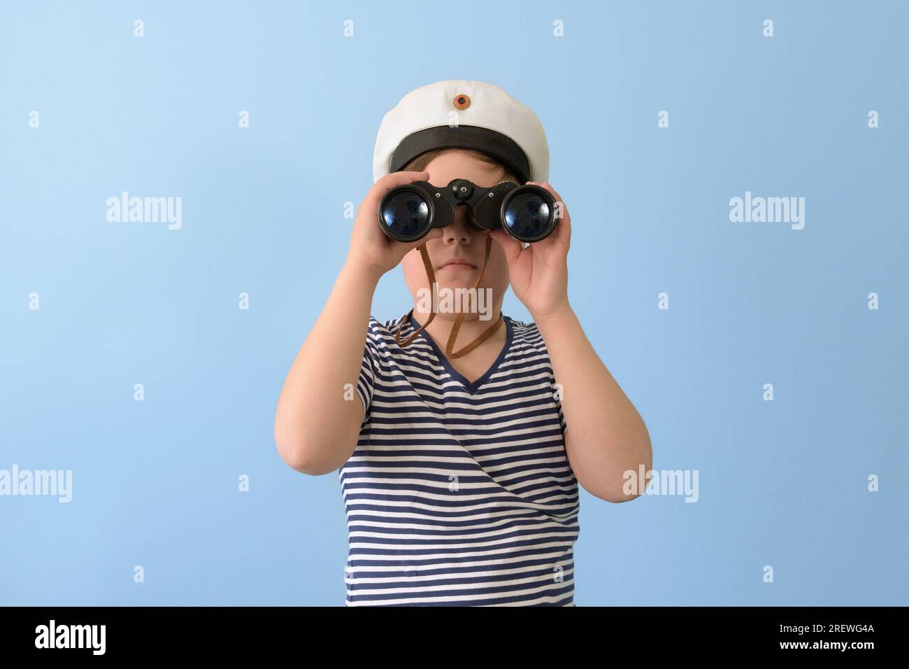 Sailor boy on a blue background in a sailor suit with binoculars ...