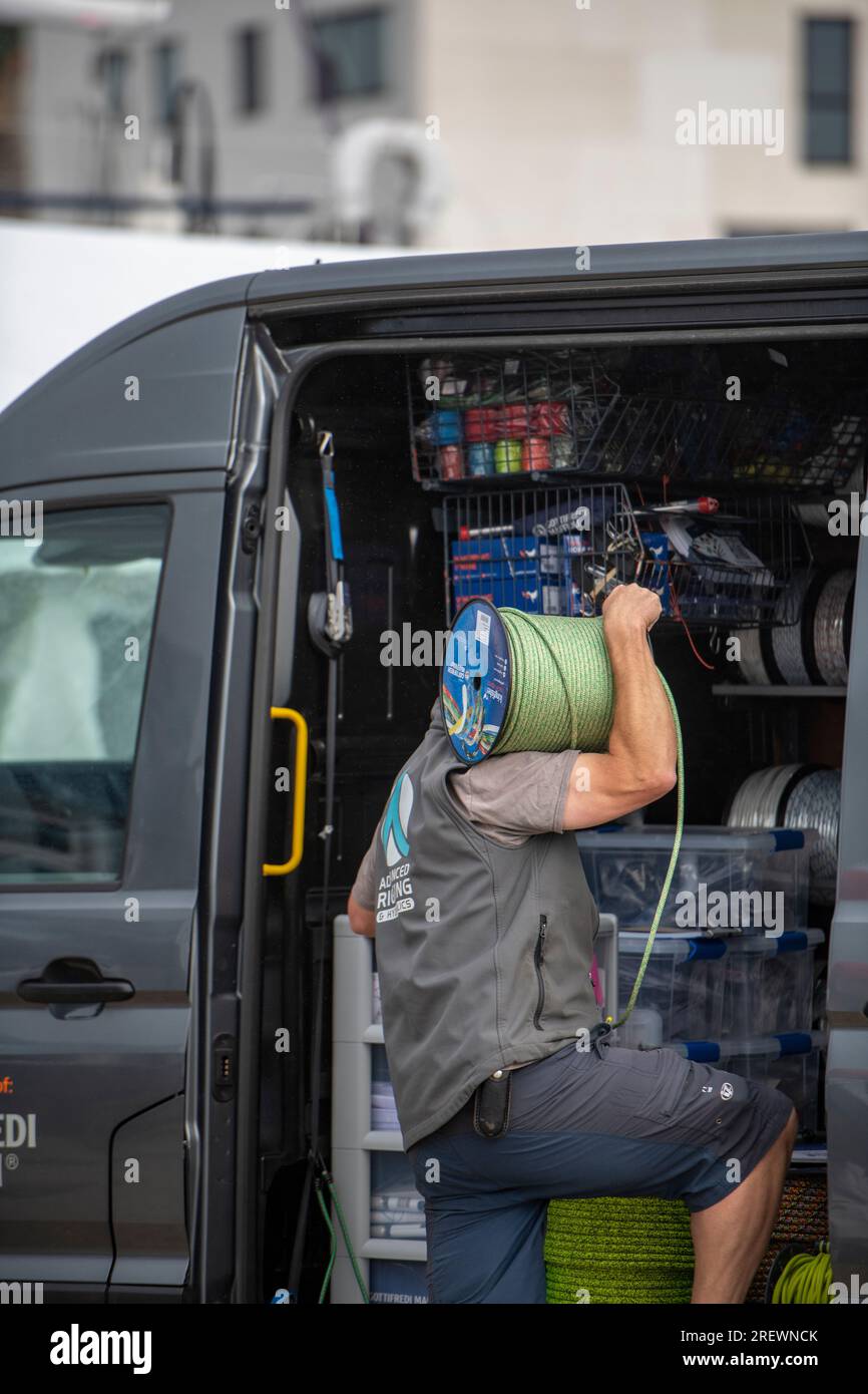 worker loading a van with a large coil of rope on his shoulder. rope ...