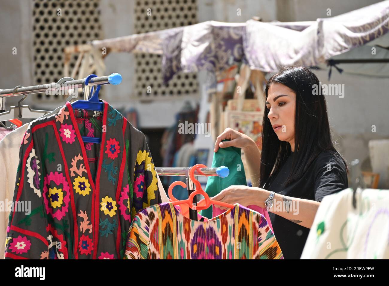 Beautiful uzbek girl sell traditional handmade clothes in her shop in ...