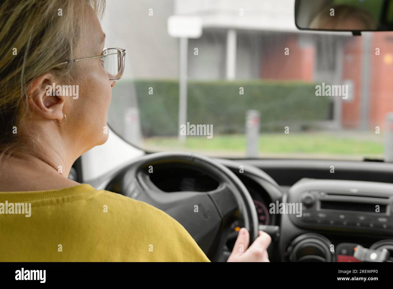 A woman with glasses driving a car makes a right turn. View from the ...