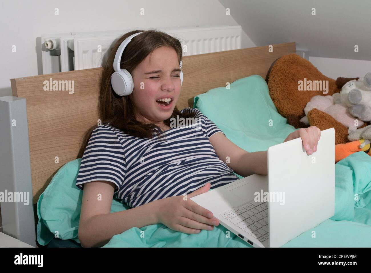 Girl schoolgirl in a bad mood with a computer in bed. Falling asleep ...
