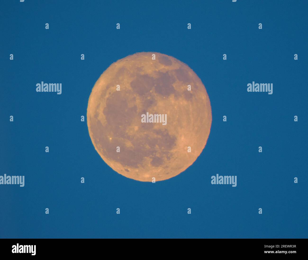 Orange colored moon through telescope at sunrise Stock Photo - Alamy